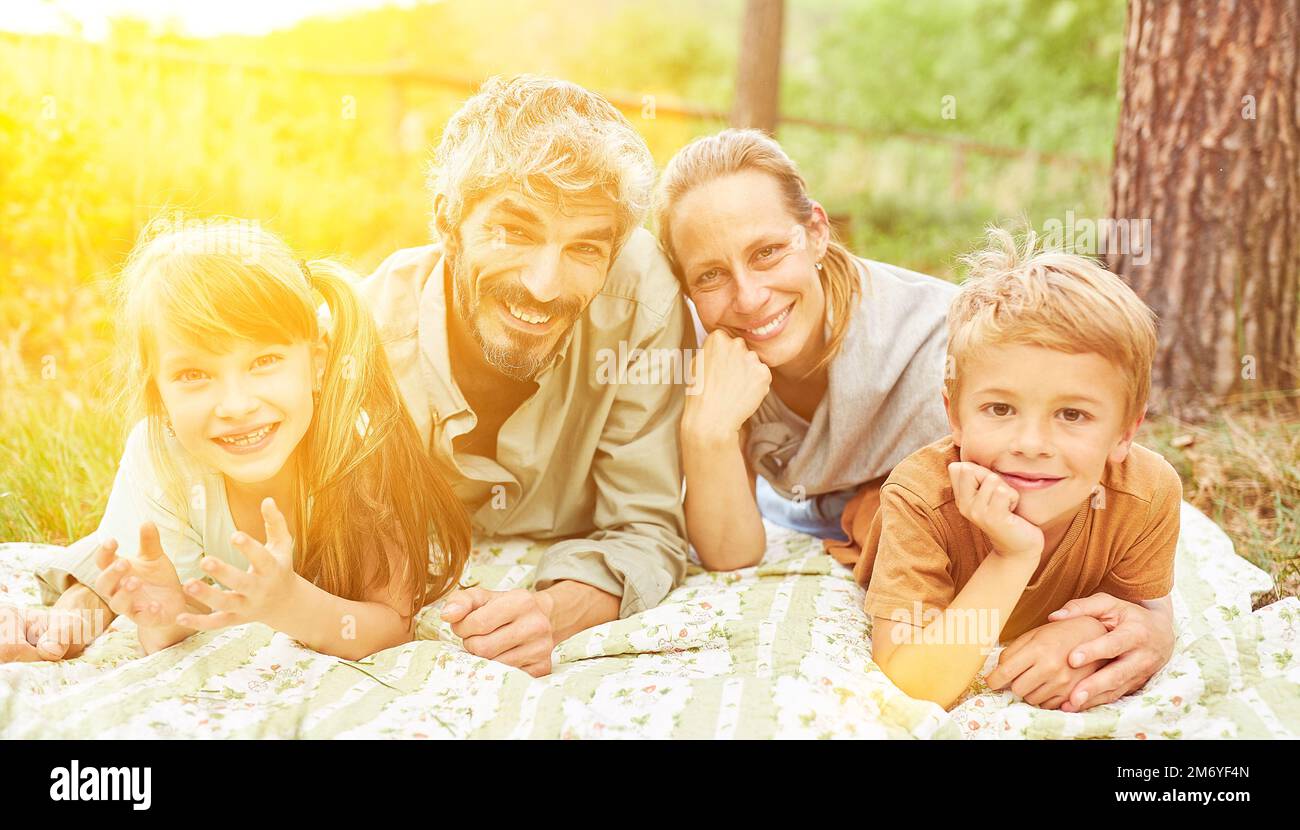 Smiling family with two children lying in park in nature in summer ...