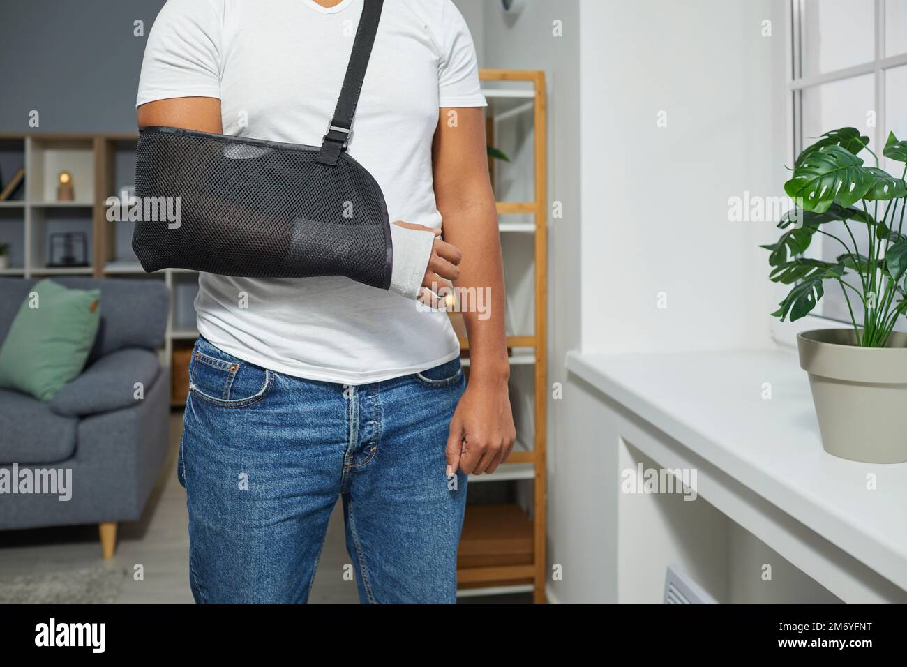 Young man wears a medical arm sling and a bandage to take care of his ...