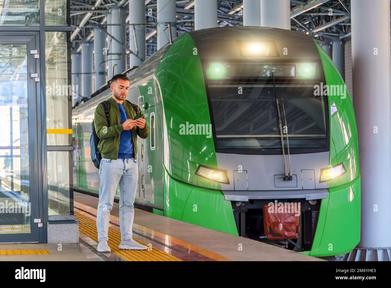 Caucasian man traveler in green windbreaker and with backpack stands on ...
