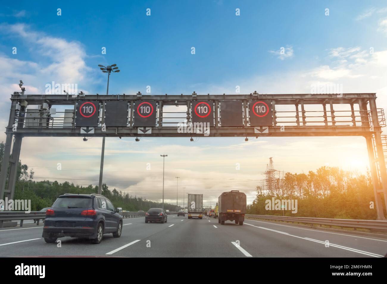 Dense stream of trucks and cars on a highway with speed signs of 110 km ...