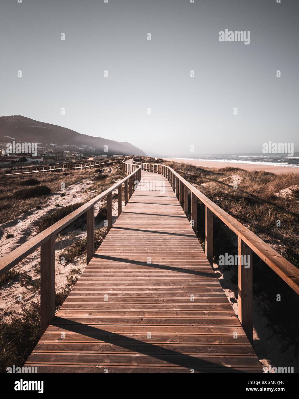 A long boardwalk on a grassy sand dune at the beach leading to the ...