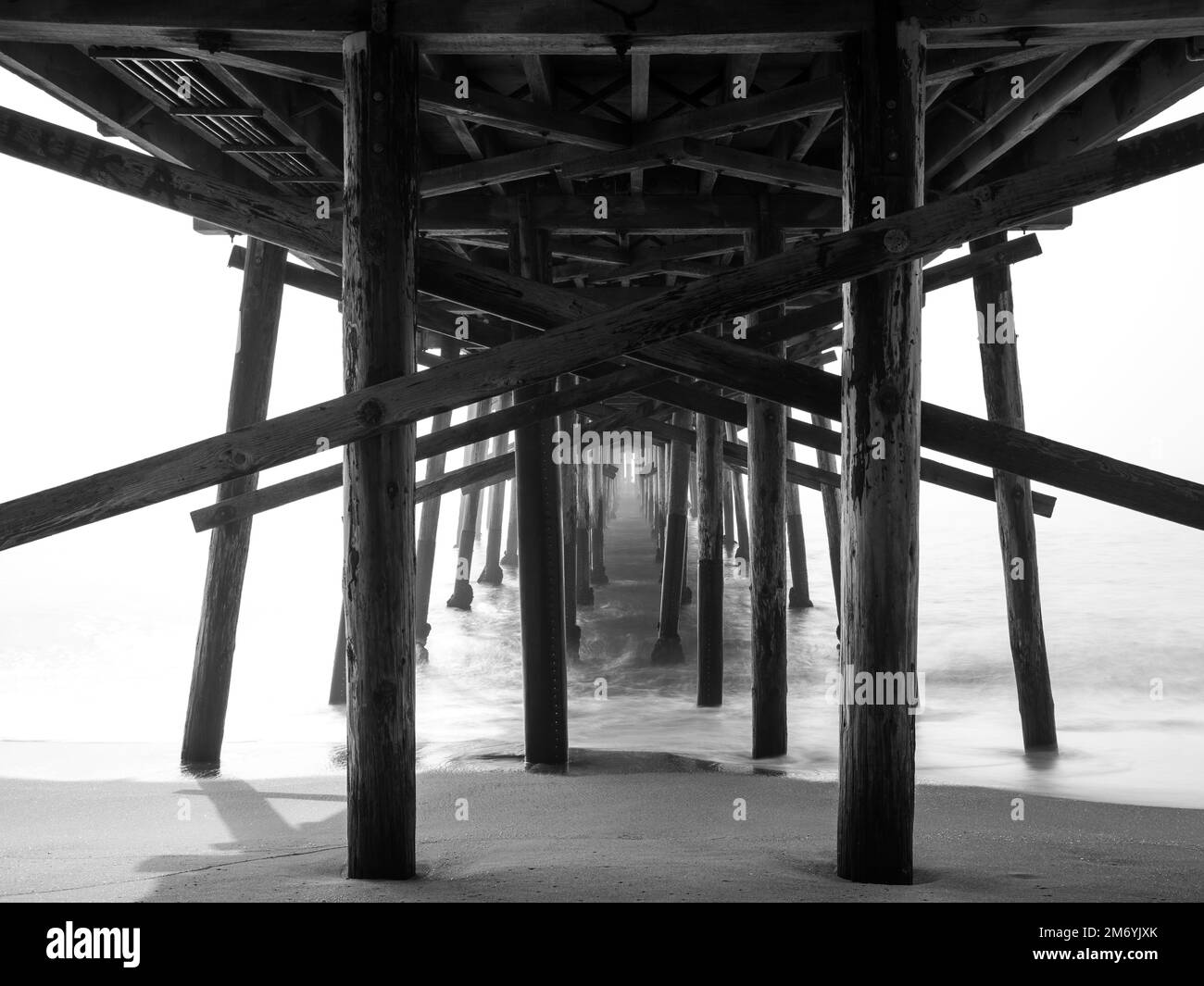 A grayscale of an sandbridge pier made of wood with supporting piles ...