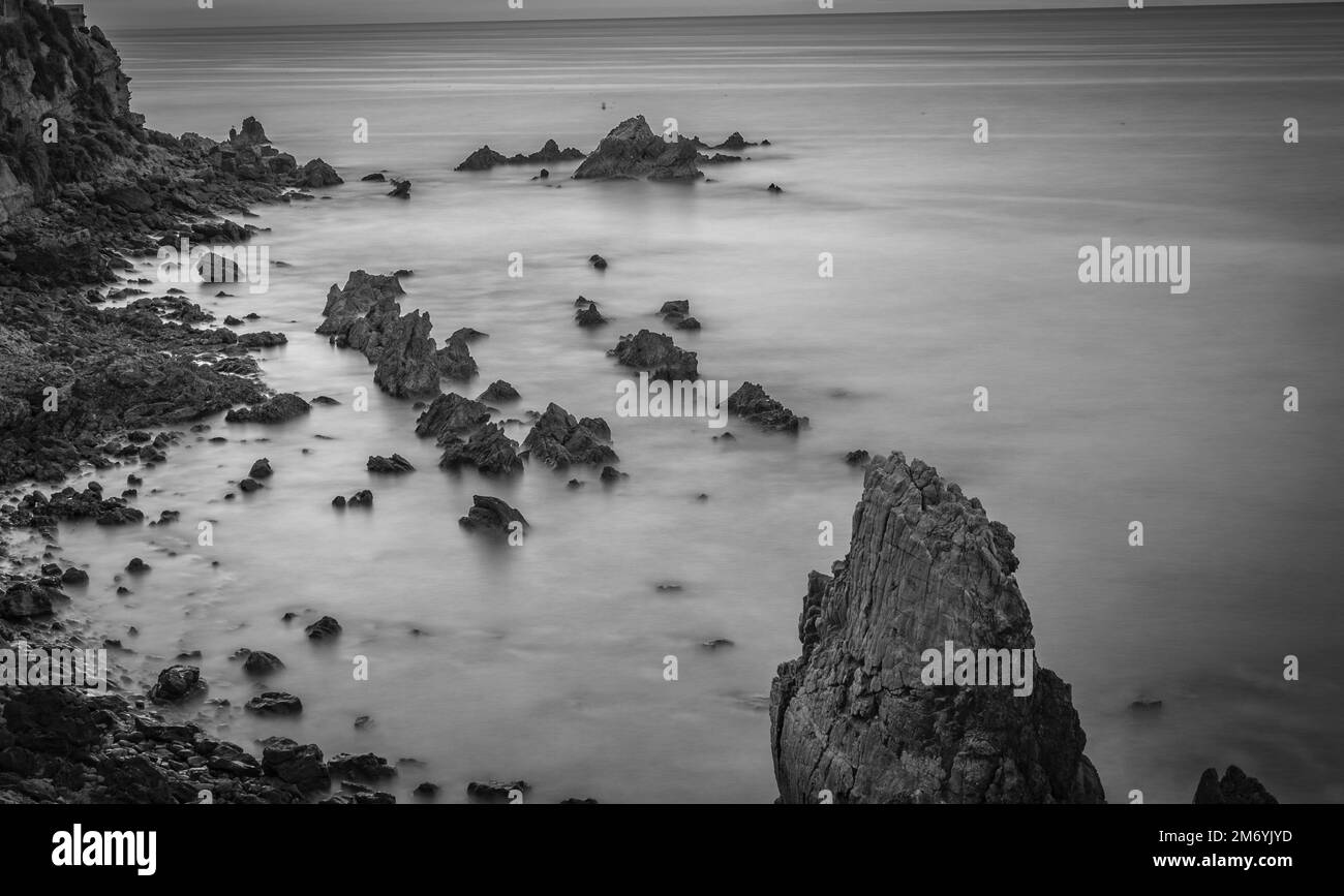 An aerial grayscale of pieces of sharp rocks in the quiet sea Stock ...