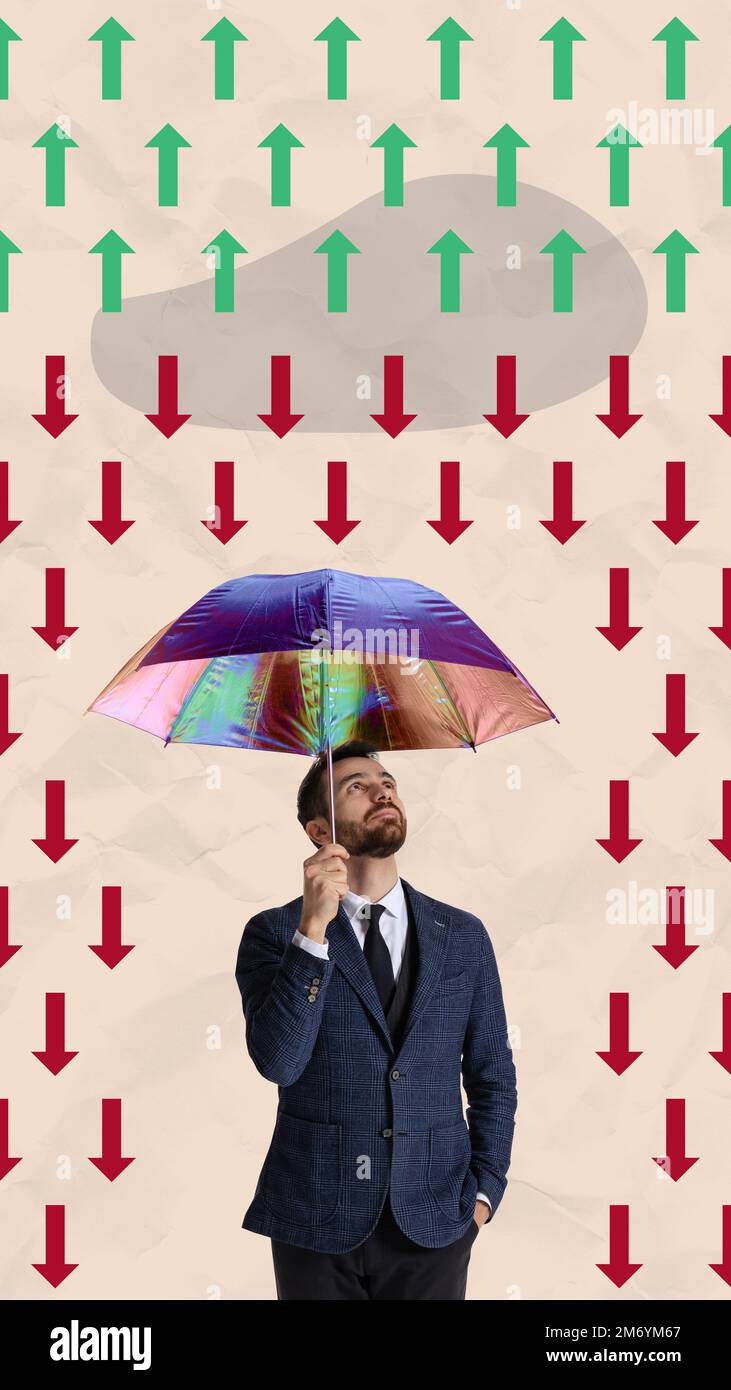 Young man standing with umbrella over light background with up and down ...