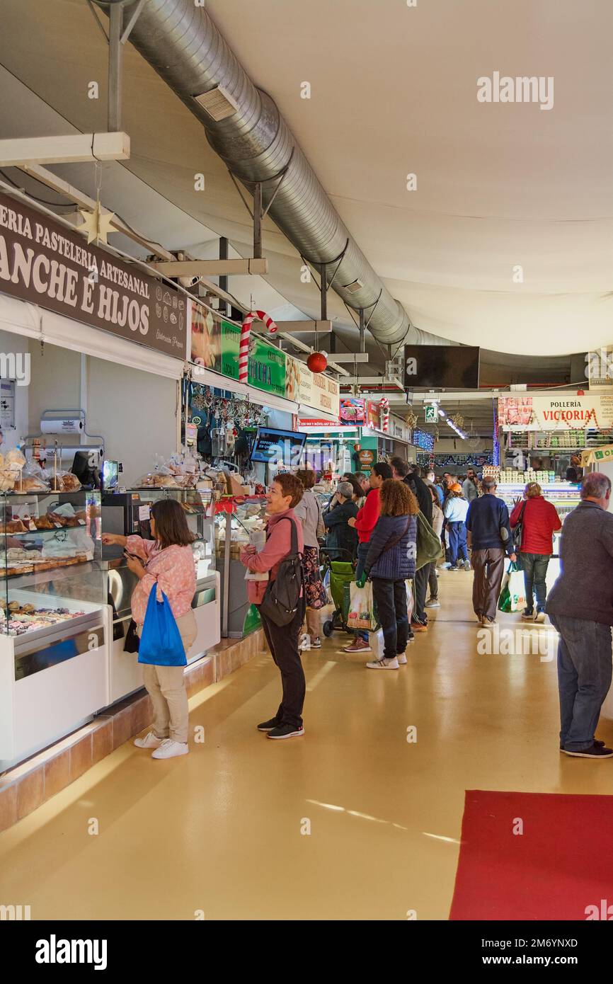 People doing their daily shopping in a municipal market full of stores ...