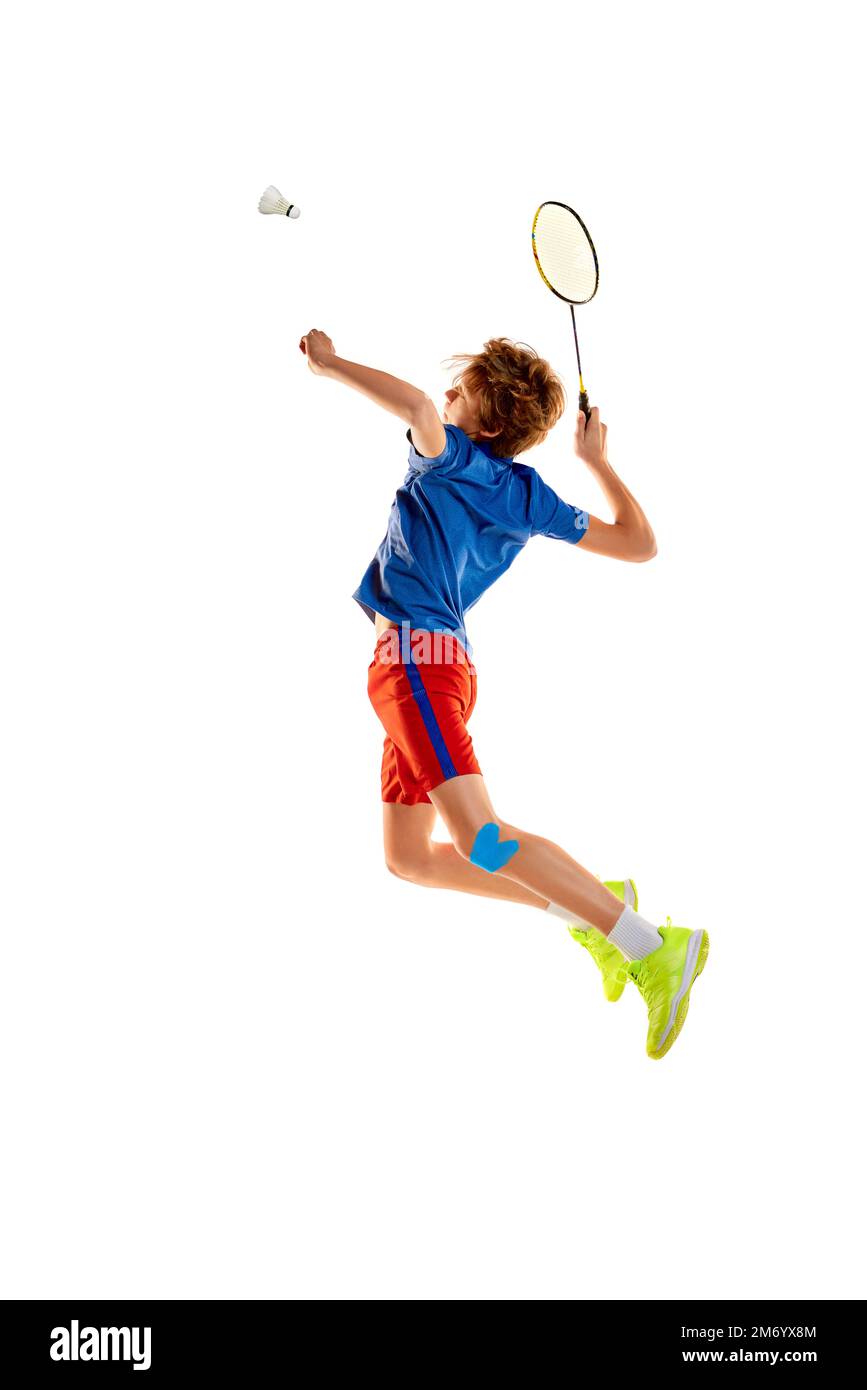 Portrait of teen boy in uniform playing badminton, serving shuttlecock ...