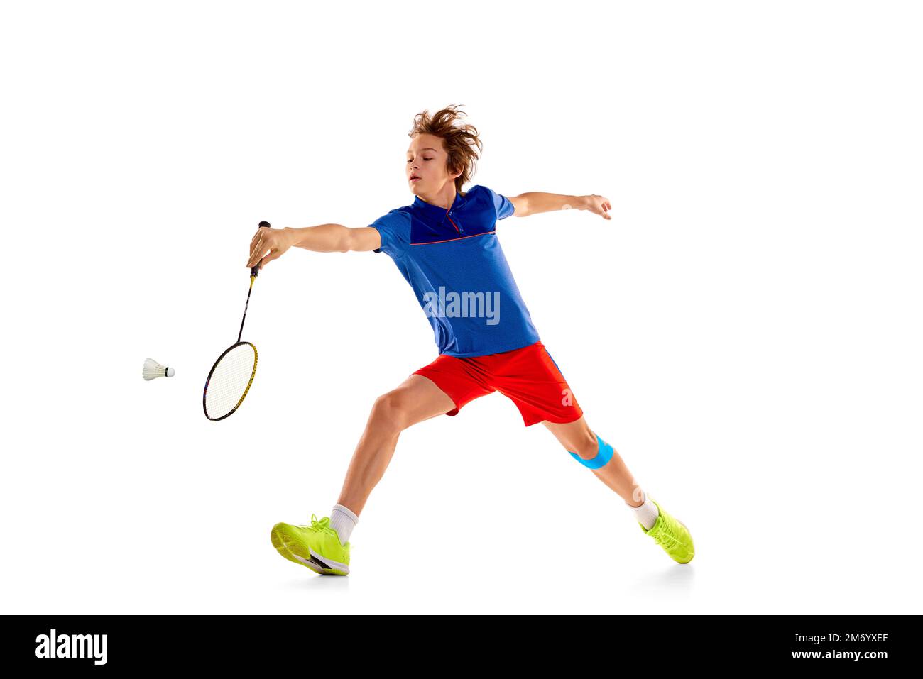 Portrait of teen boy in uniform playing badminton, gitting shuttlecock ...