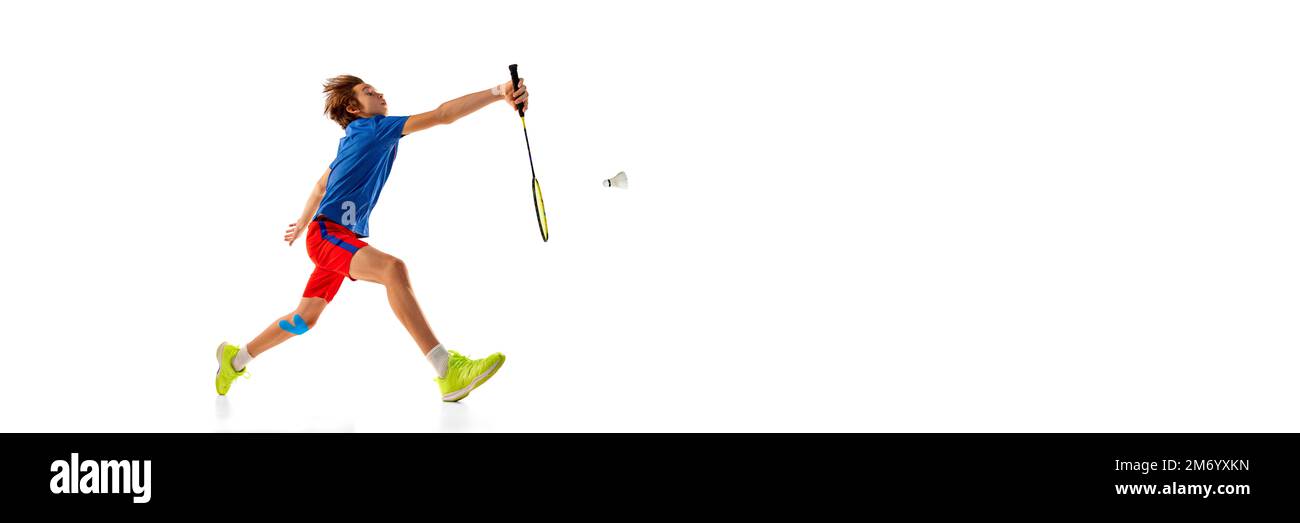 Portrait of teen boy in uniform playing badminton, hitting shuttlecock ...