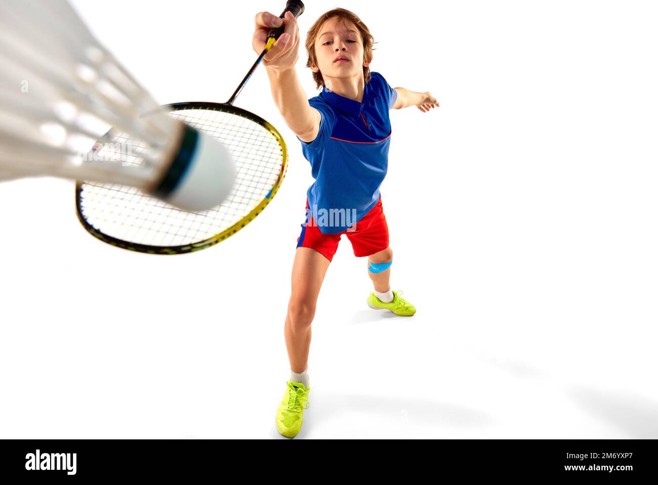 Concentrated teen boy in uniform playing badminton, hitting shuttlecock ...