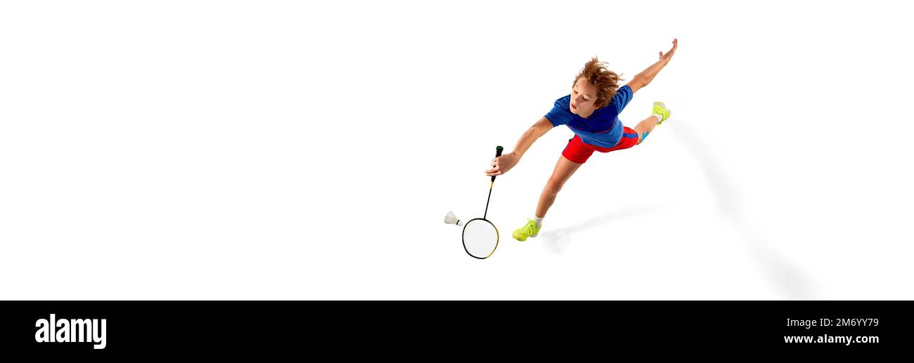 Portrait of teen boy in uniform playing badminton, hitting shuttlecock ...