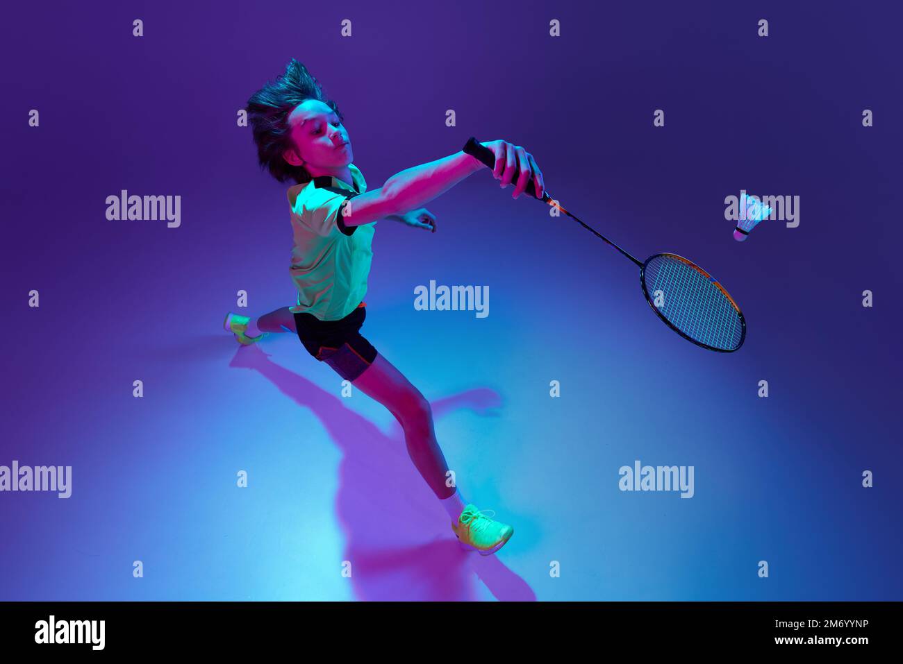 Top view. Portrait of teen boy in uniform playing badminton over blue ...