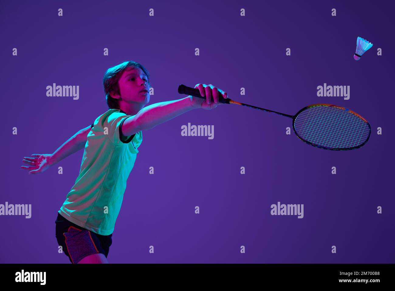 Portrait of teen boy in uniform playing badminton, hitting shuttlecock ...