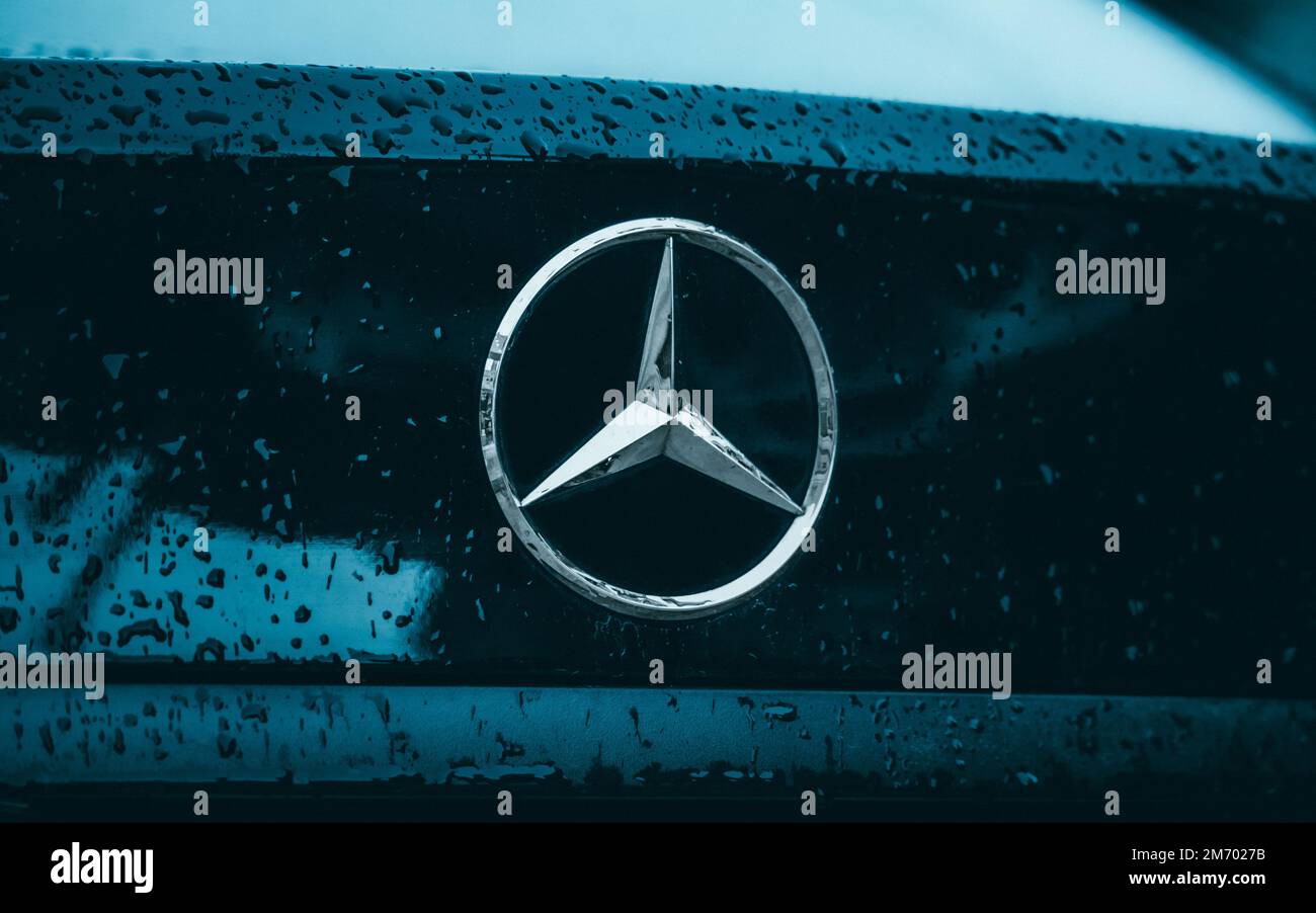 A closeup of the Mercedes c200 logo and emblem on the wet, blue trunk ...