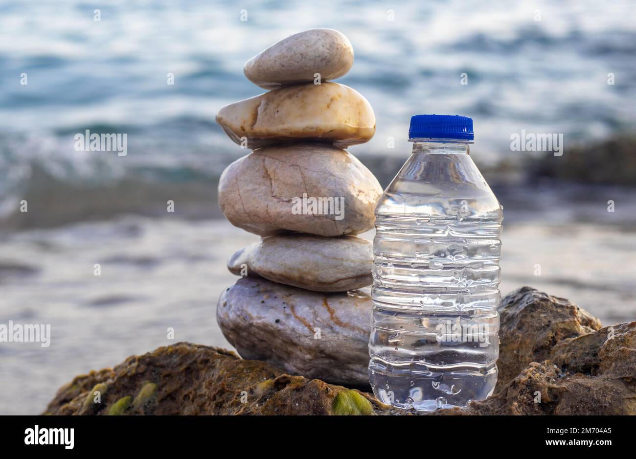 pebbles in pyramid one over another and bottle with drinking water on ...