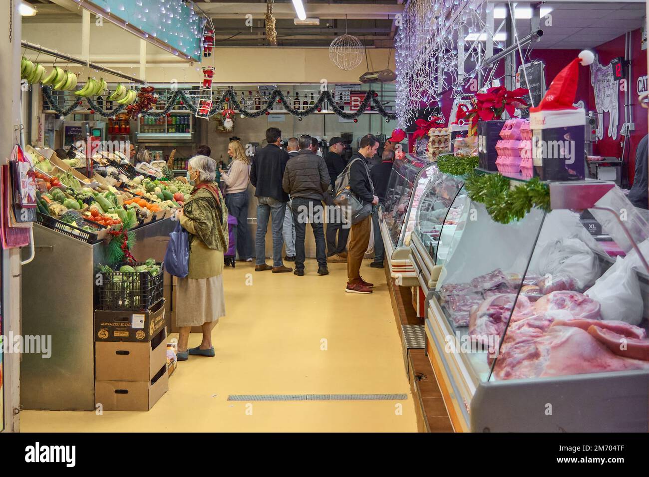 People doing their daily shopping in a municipal market full of stores ...