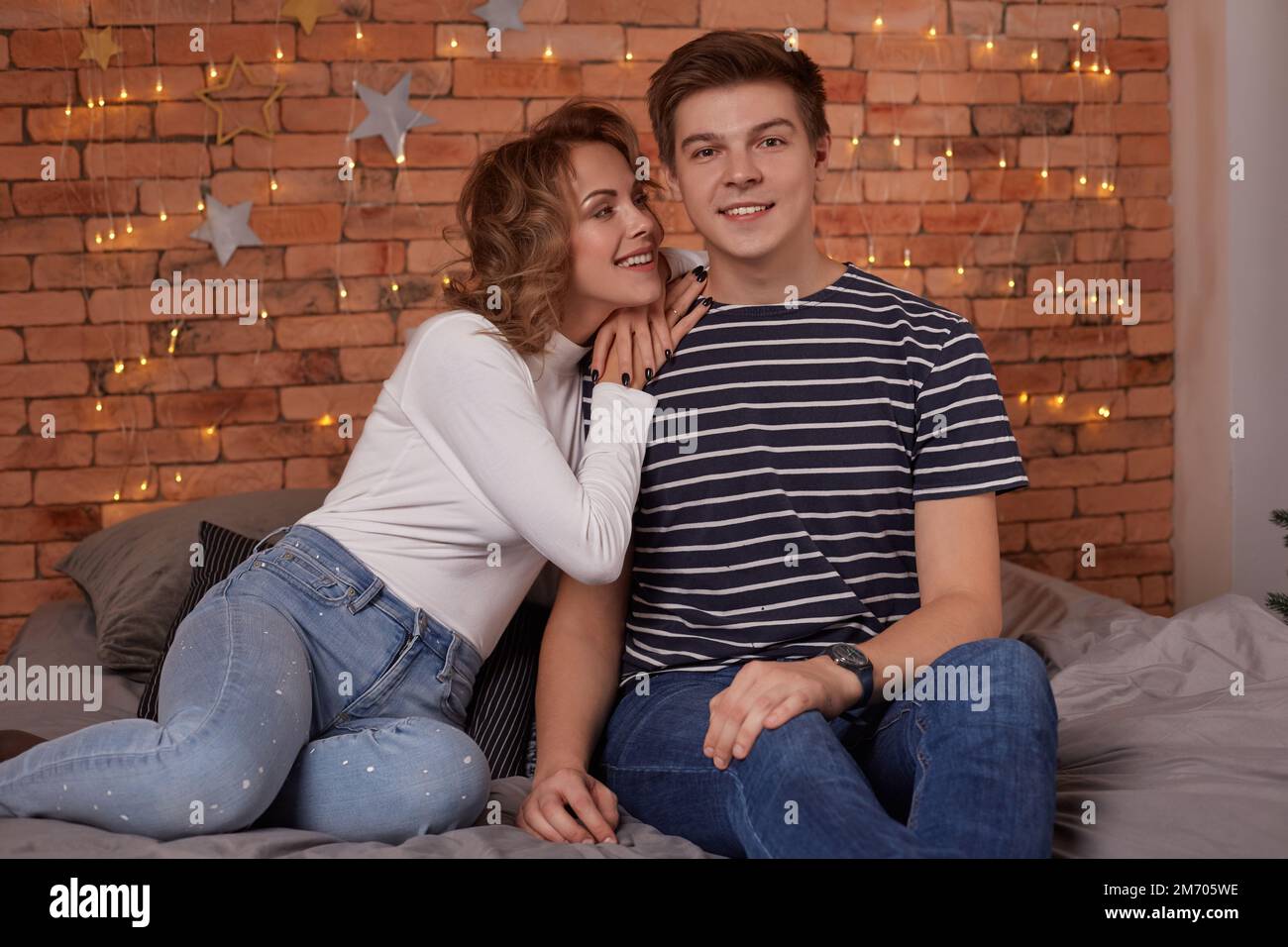 Happy loving couple relaxing on bed at home, young woman touching ...