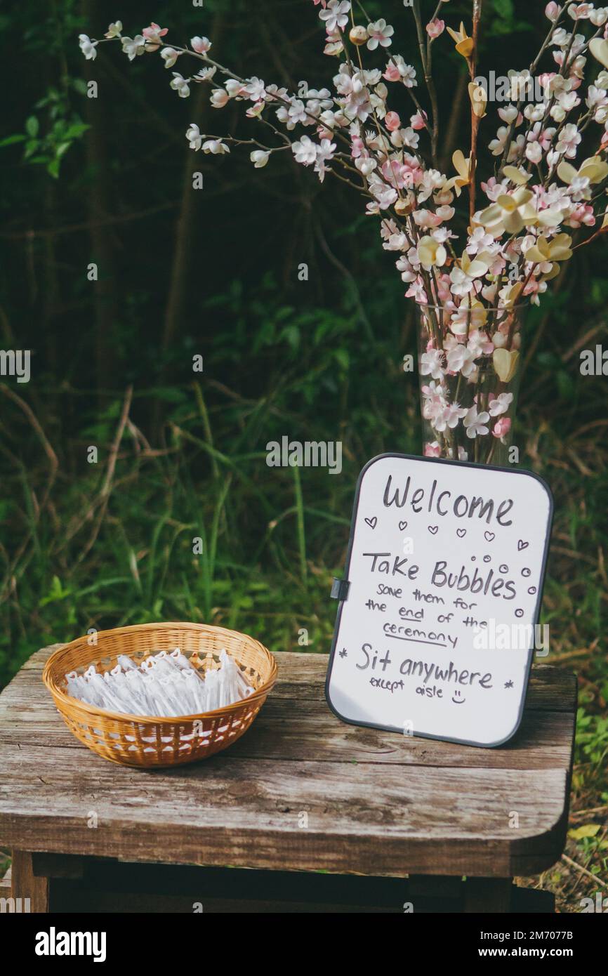 Backyard wedding welcome table with basket of bubbles for ceremony exit ...