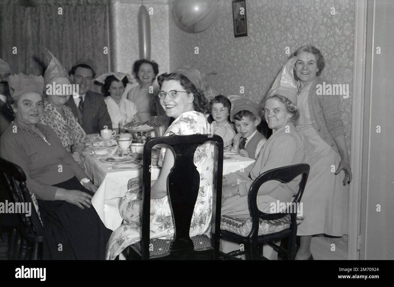 1950s, historical,big smiles as a family sits around a table having ...