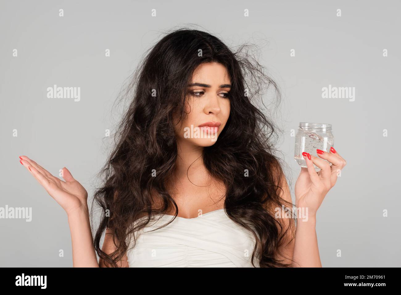 brunette woman with tangled hair showing shrug gesture while holding ...