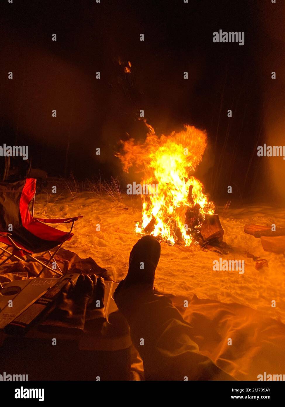 A vertical shot of a large burning bonfire on a beach camping site ...