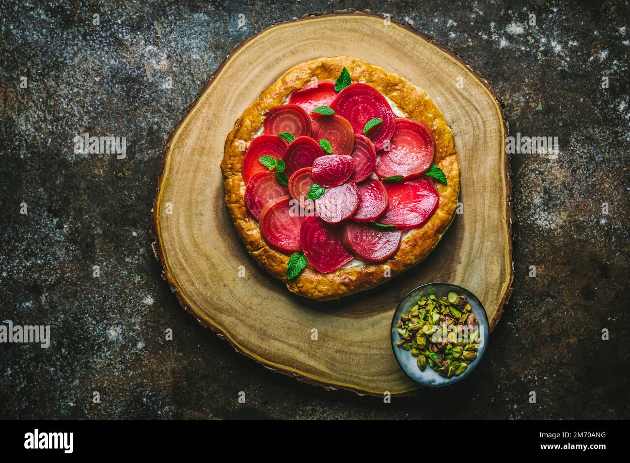 Round pastry tart with sliced beets, feta and mint leaves on wooden ...
