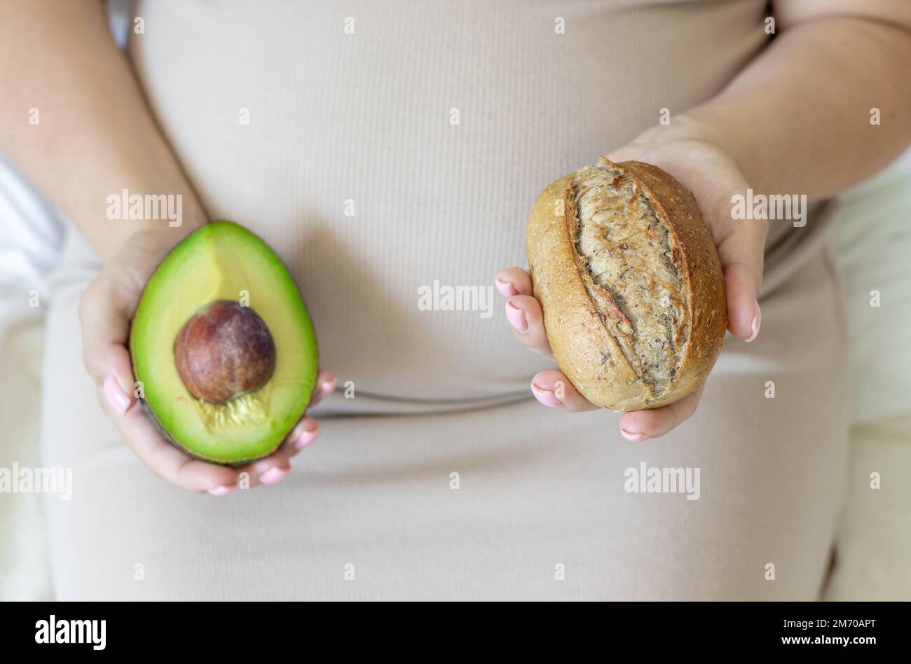 pregnant woman on bed advanced belly with avocado bun baby clothes in ...