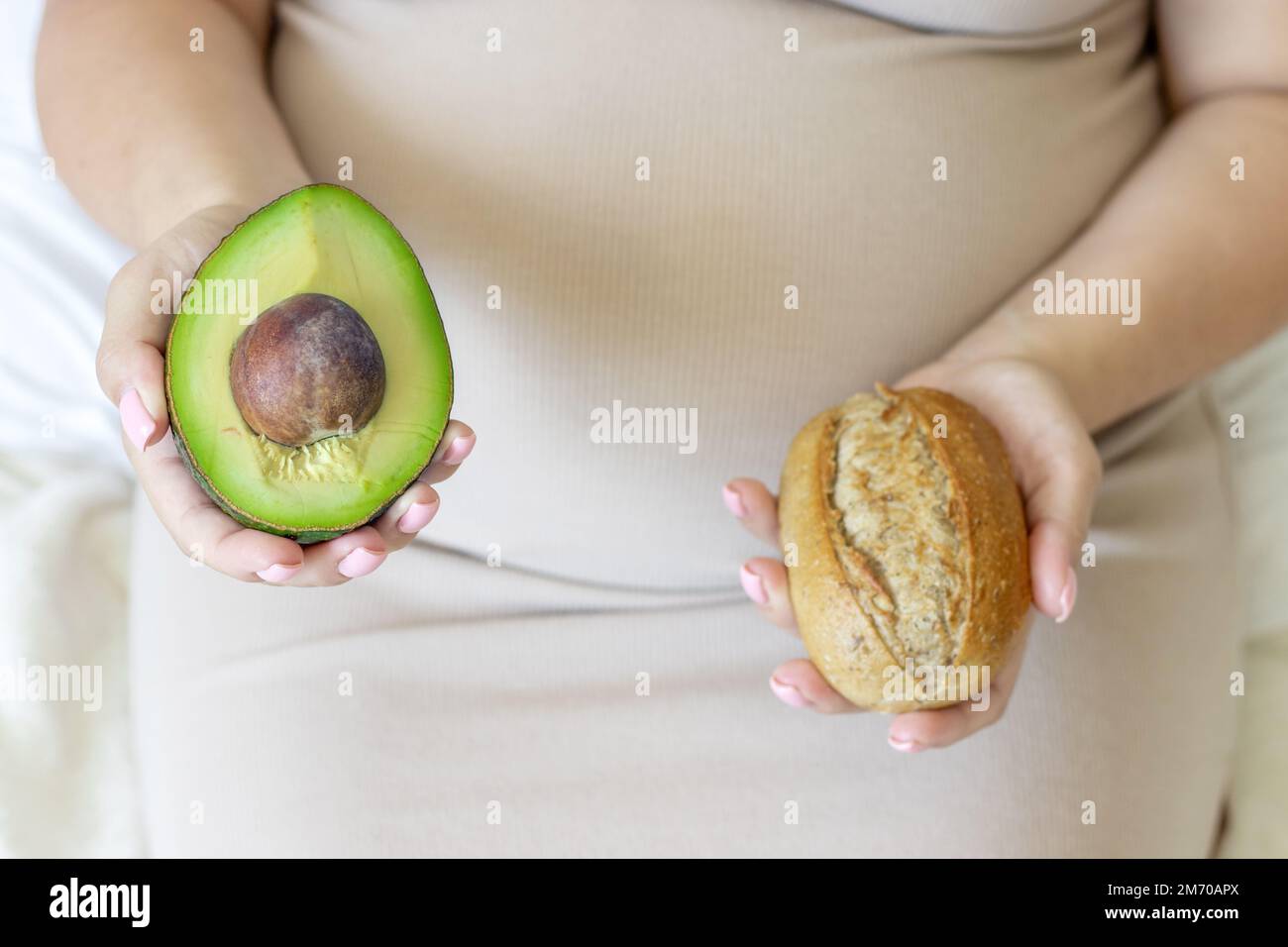 pregnant woman on bed advanced belly with avocado bun baby clothes in ...