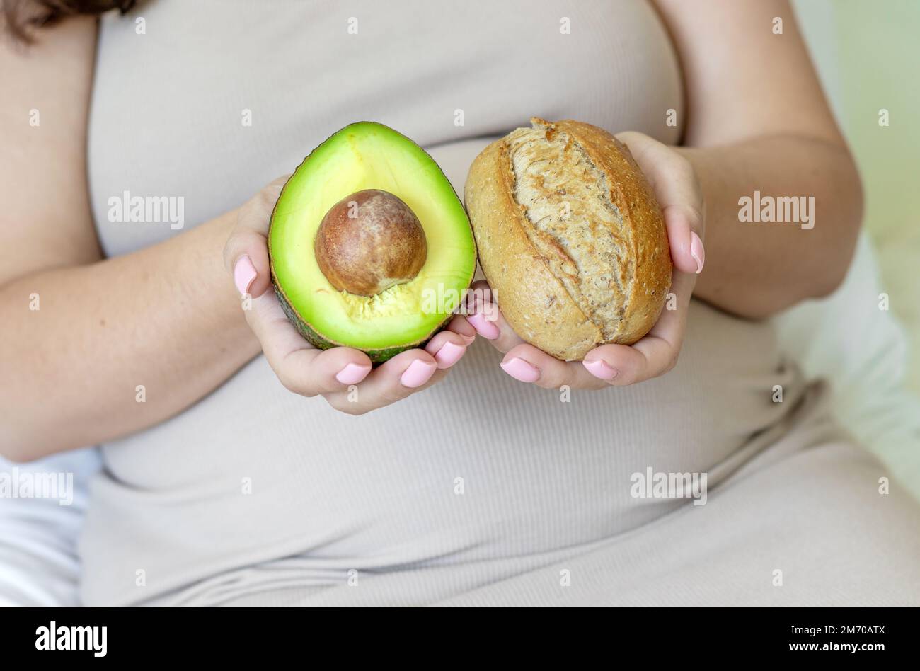 pregnant woman on bed advanced belly with avocado bun baby clothes in ...