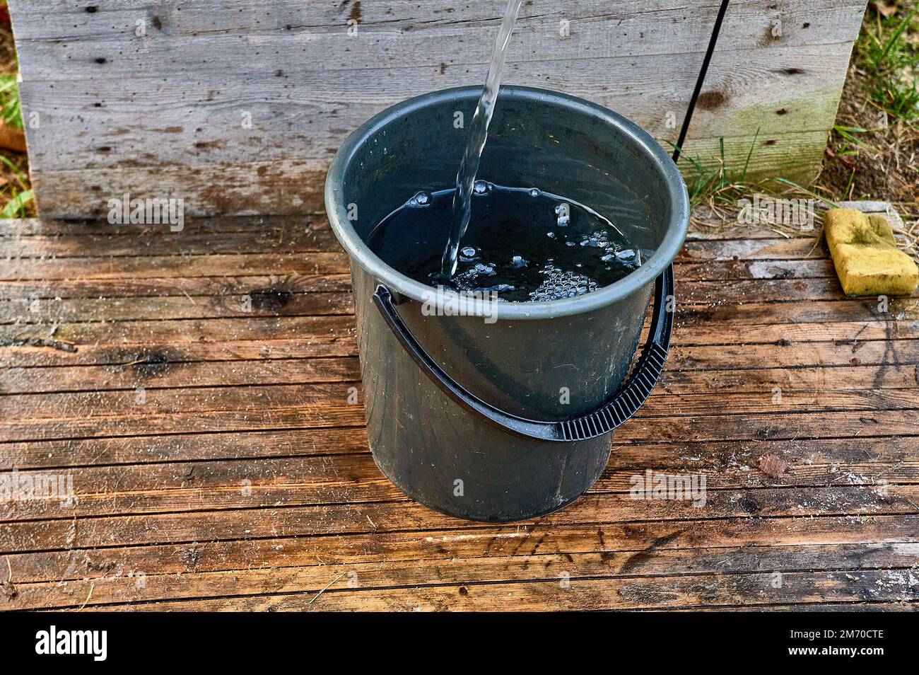 a black plastic bucket is filled with water from the pump Stock Photo ...