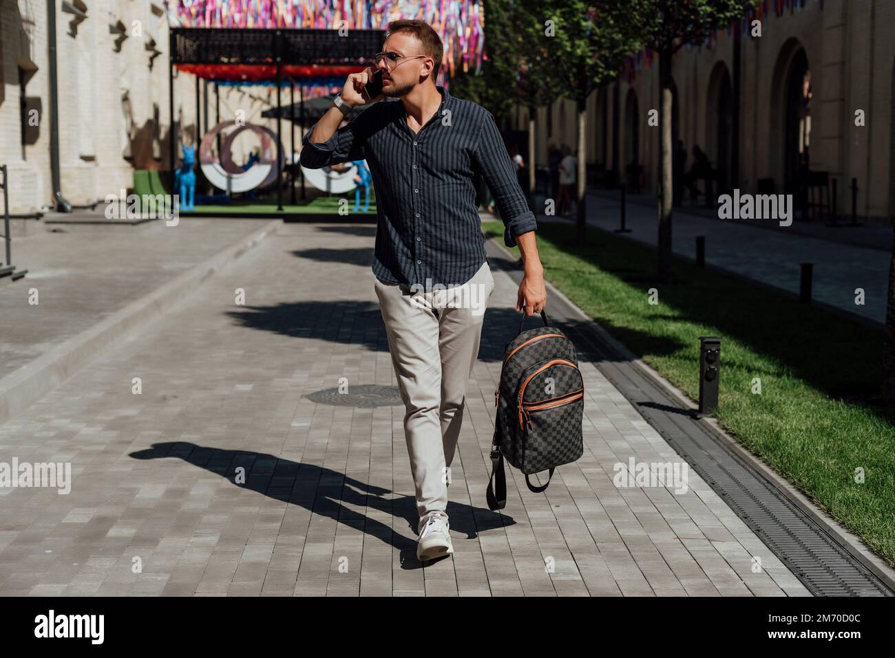 a guy in a shirt and trousers poses and walks around the city Stock ...