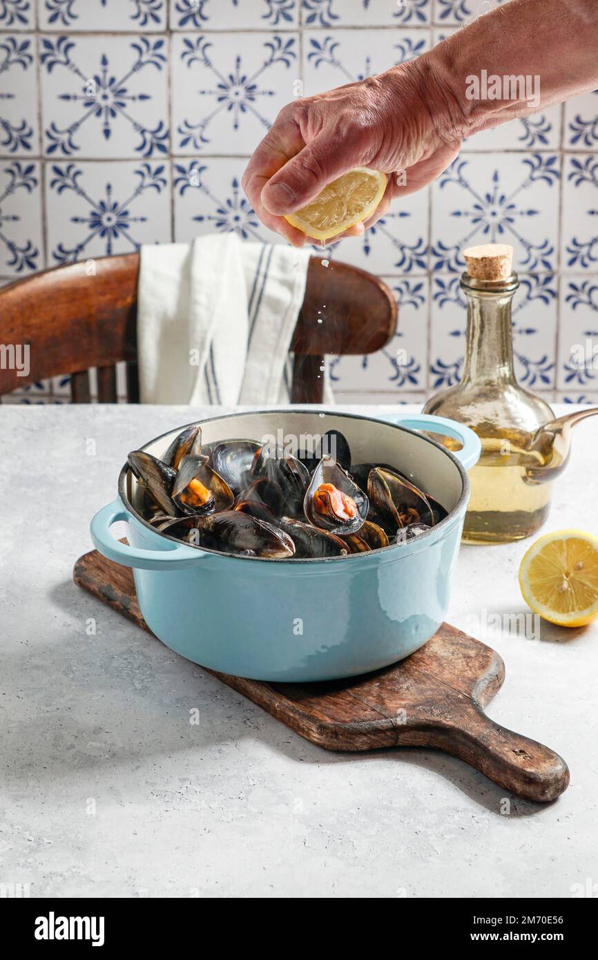mussels in white wine and lemon juice in a blue cast-iron caseroll ...