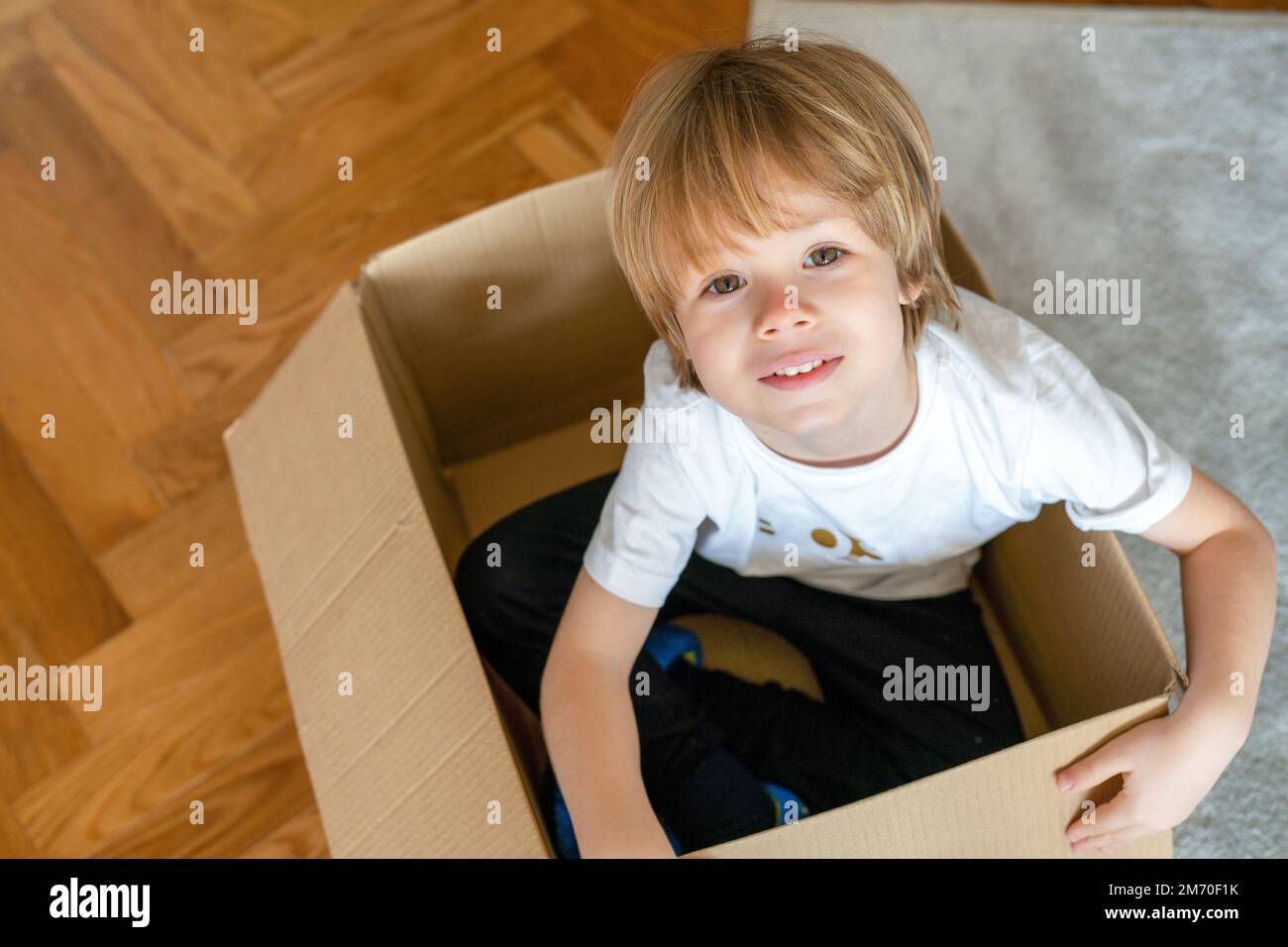 Little kid boy having fun in his new home with a cardboard box Stock ...