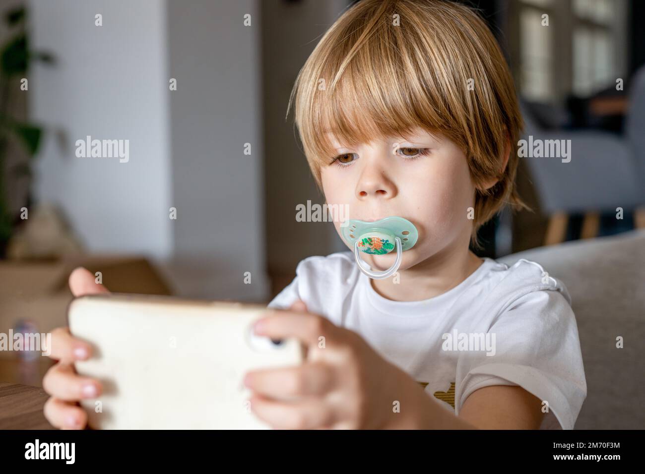 Close up cute little boy using smartphone, looking at screen, curious ...