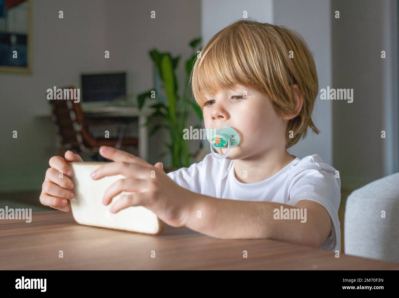 Close up cute little boy using smartphone, looking at screen, curious ...