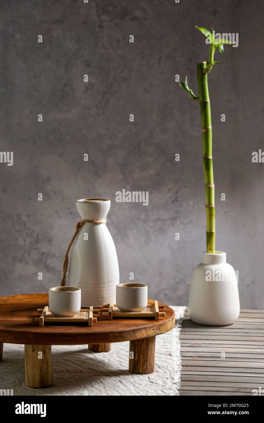 Japanese sake still life with a sprig of bamboo, light linen background ...