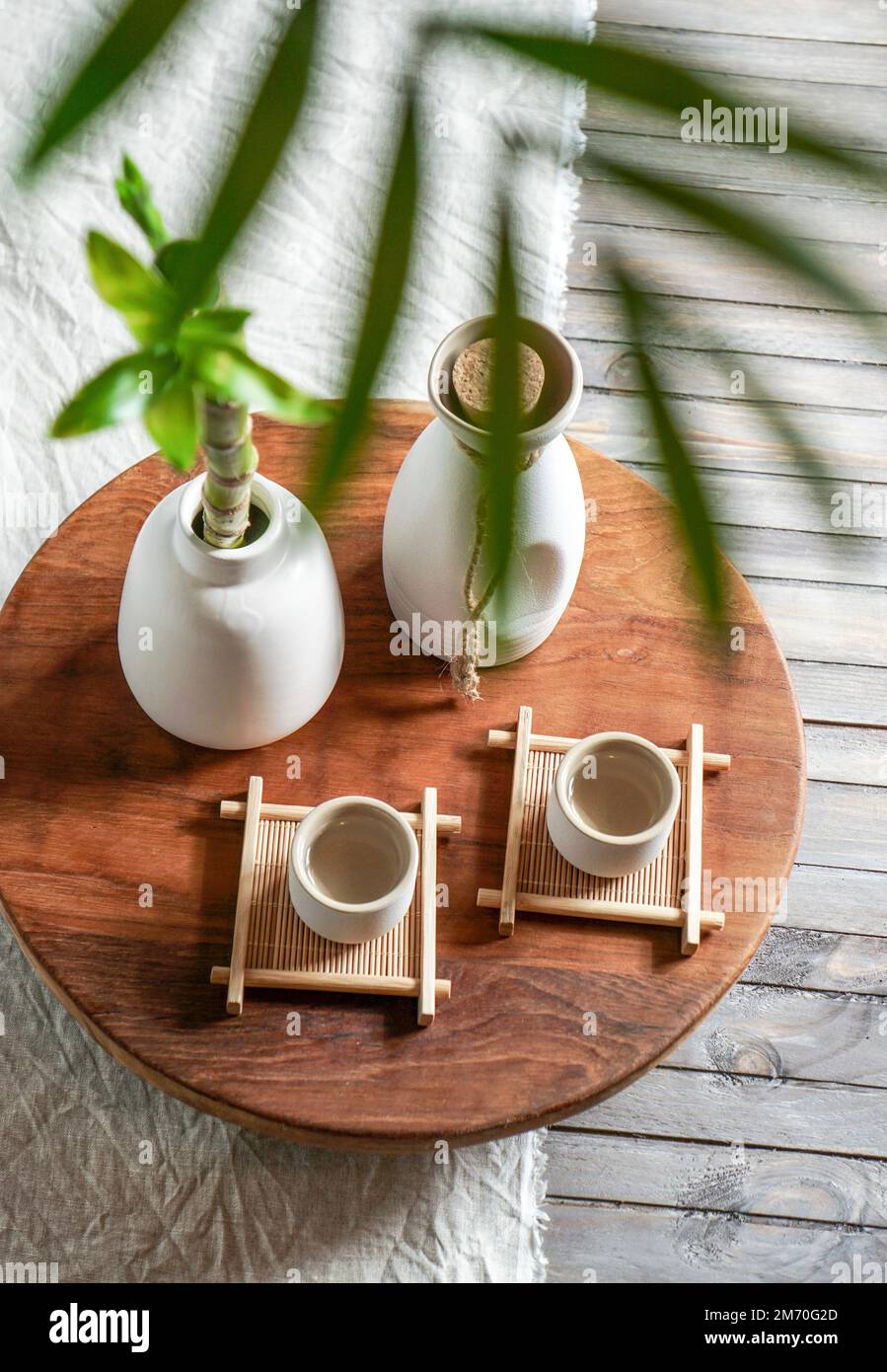 Japanese sake still life with a sprig of bamboo, light linen background ...