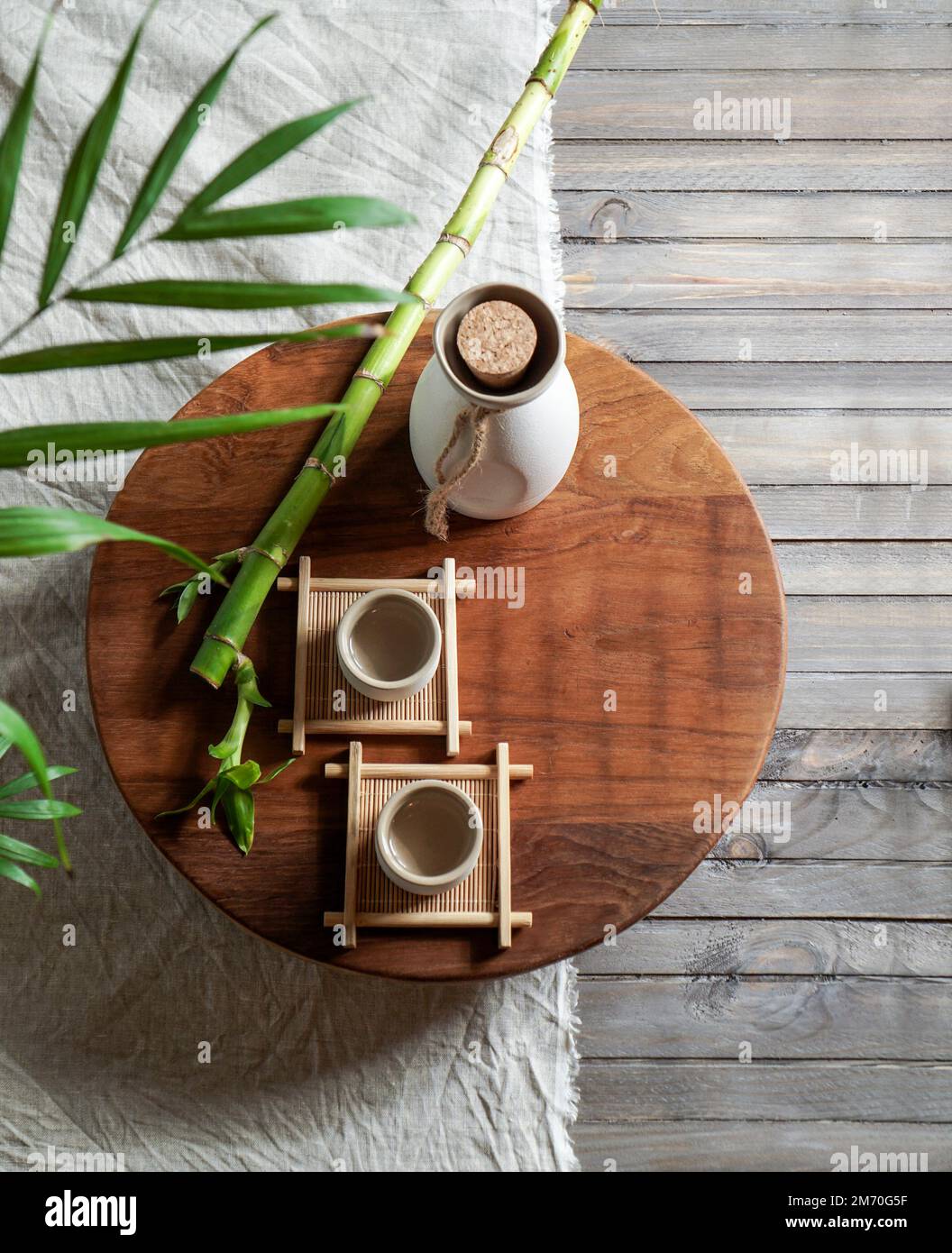 Japanese sake still life with a sprig of bamboo, light linen background ...