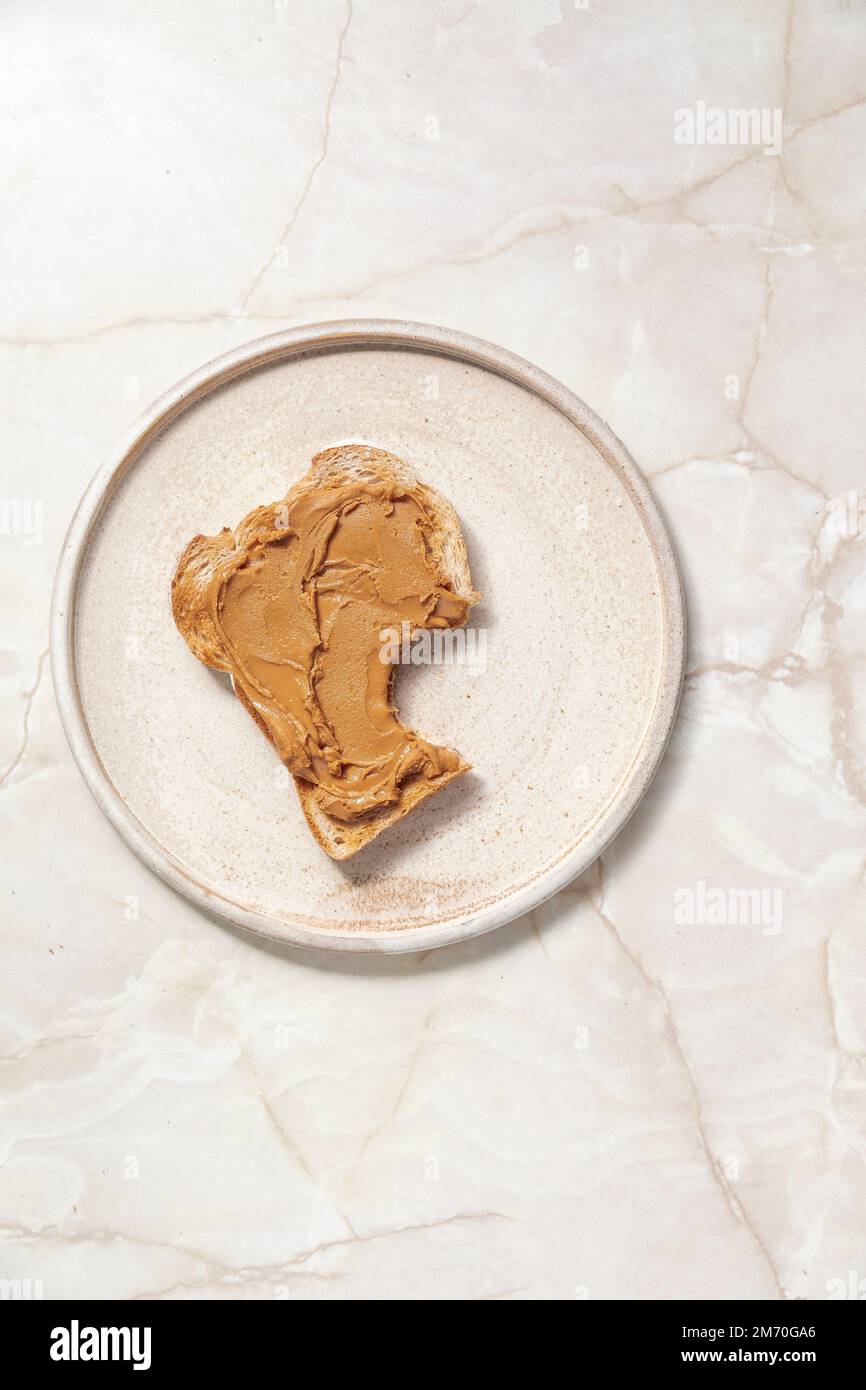 Peanut butter on toast, with bite mark on ceramic plate Stock Photo - Alamy