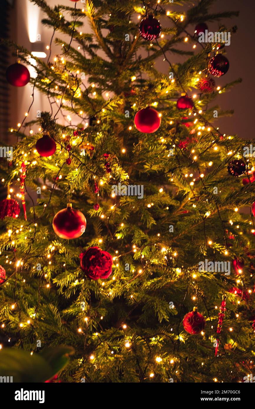 An image of a decorated Christmas tree with yellow lights and red balls ...