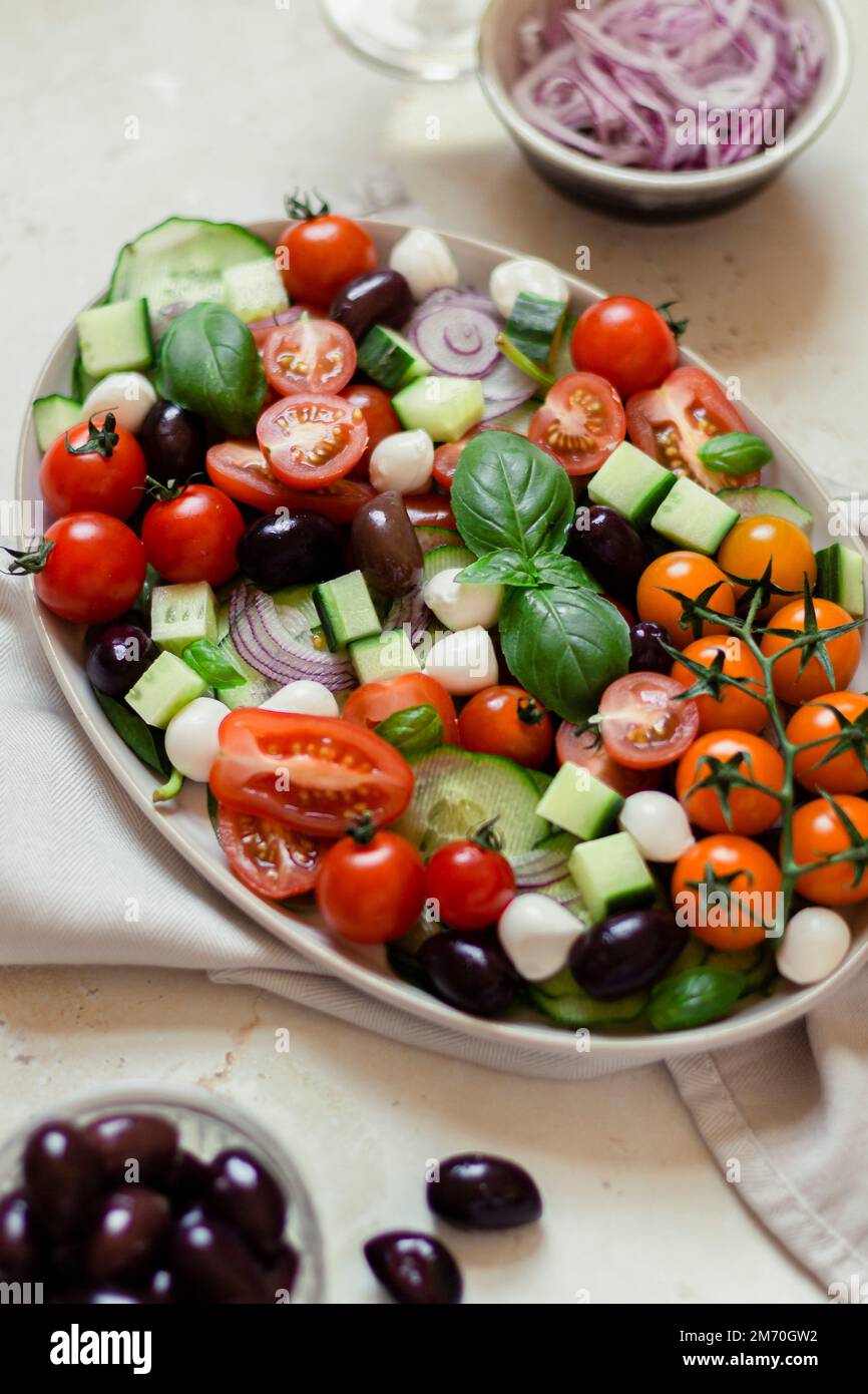 Dish with a Greek salad on a light background Stock Photo - Alamy