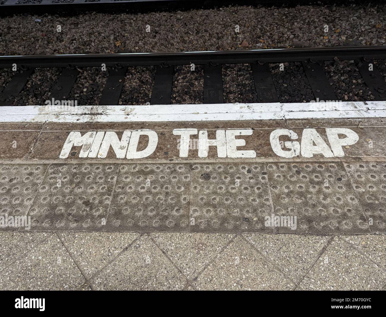 A top view of white "MIND THE GAP" sign at the train station Stock ...