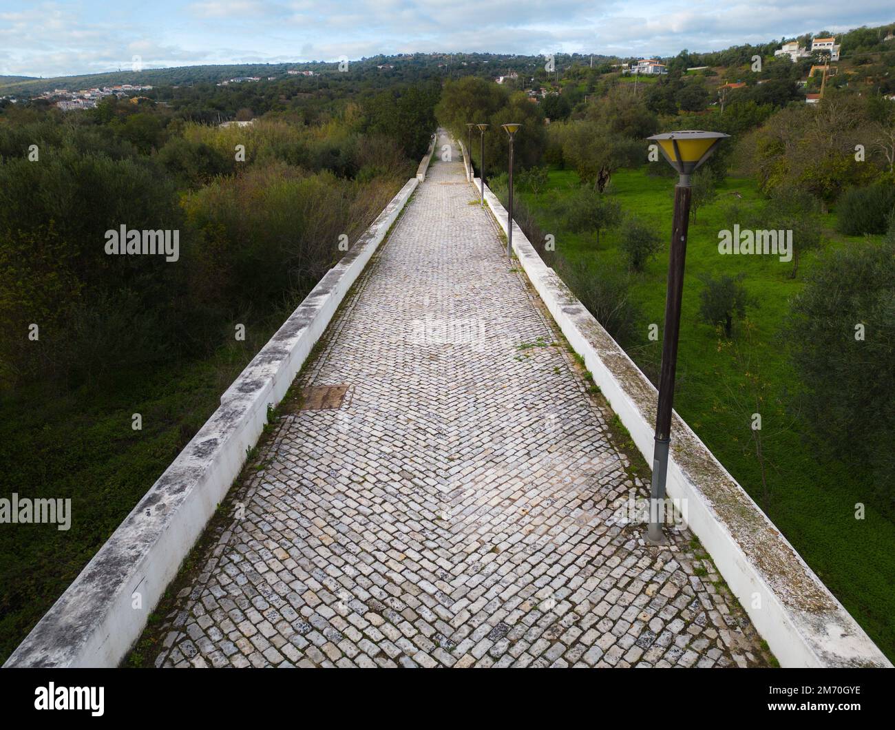 An aerial view of a cobblestone bridge stretching through lush green ...