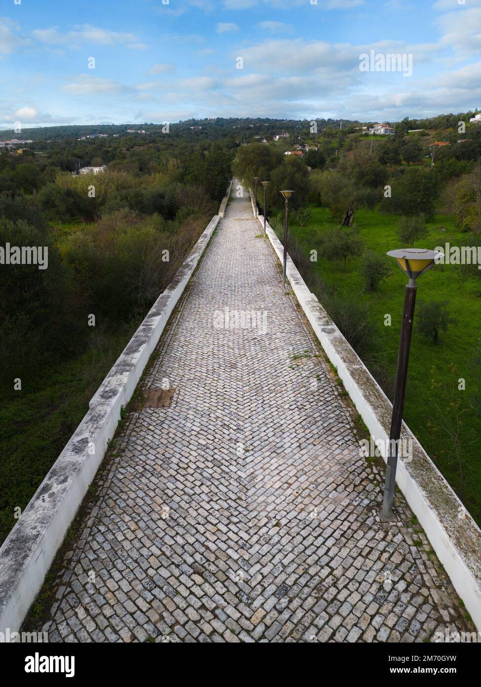 An aerial view of a cobblestone bridge stretching through lush green ...