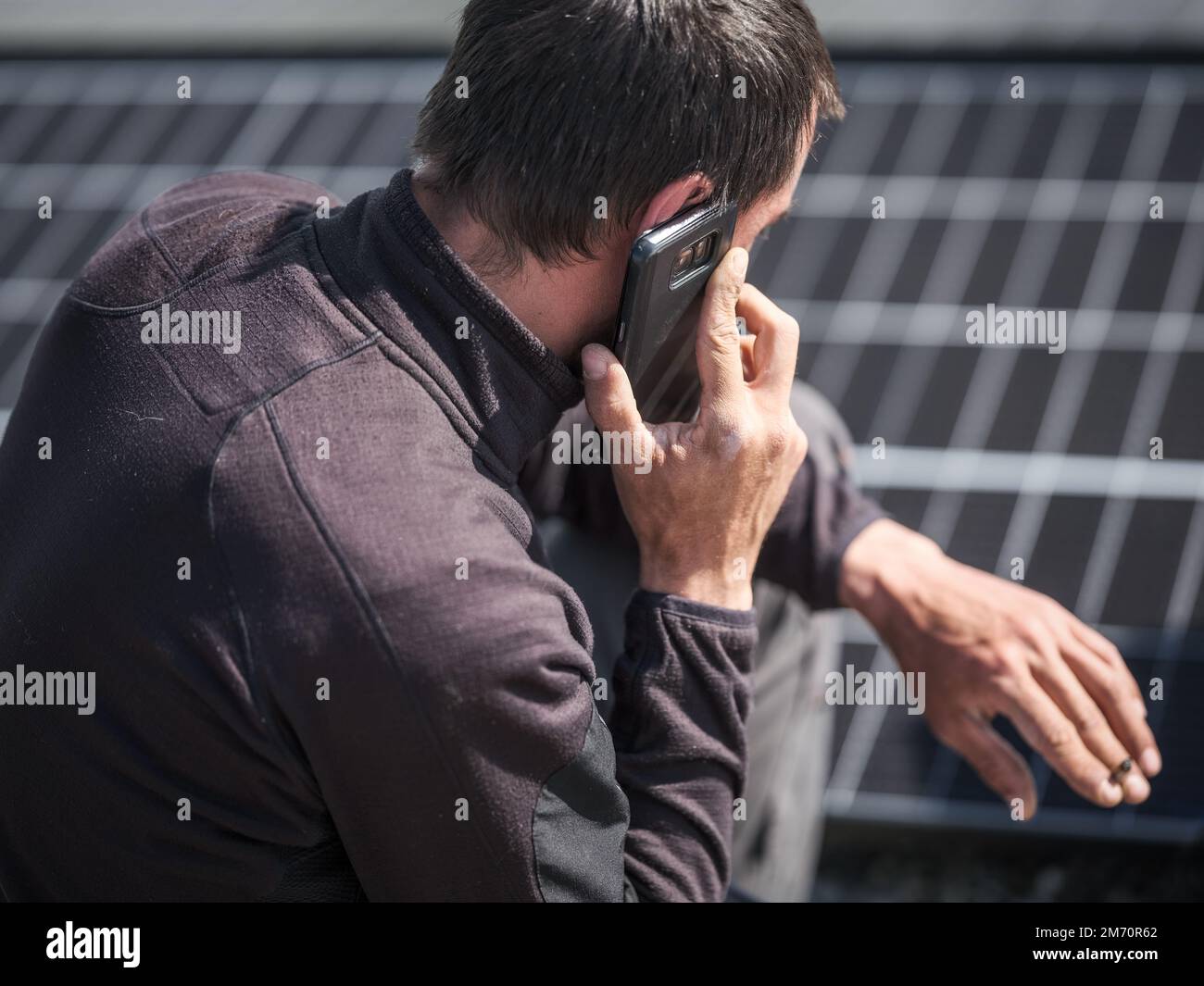 rooftop worker making phone calls with mobile phone during installation ...