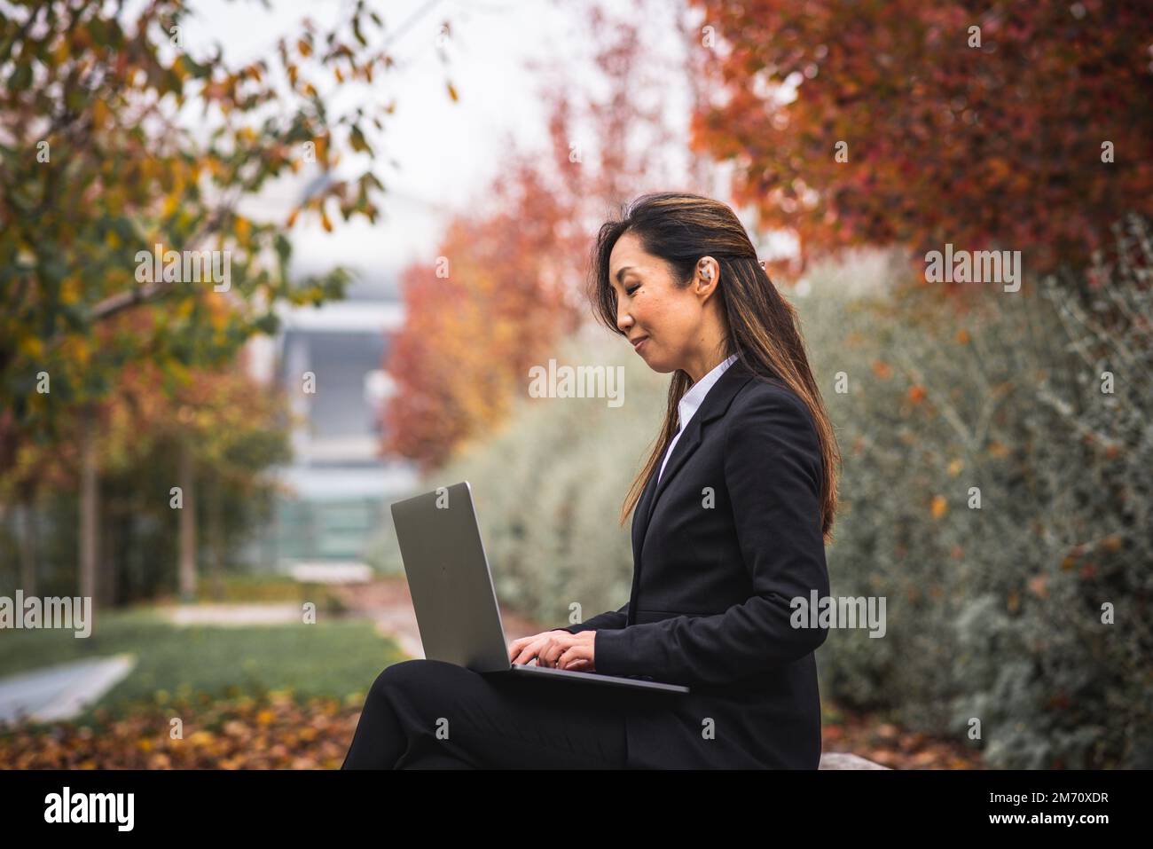 Successful Japanese woman at work with her laptop outdoors, concept of ...