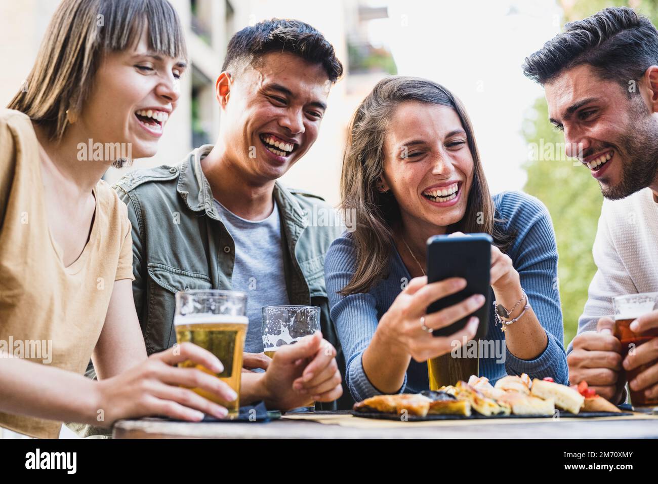 Group of friends at pub, people having fun and using smart phones to ...