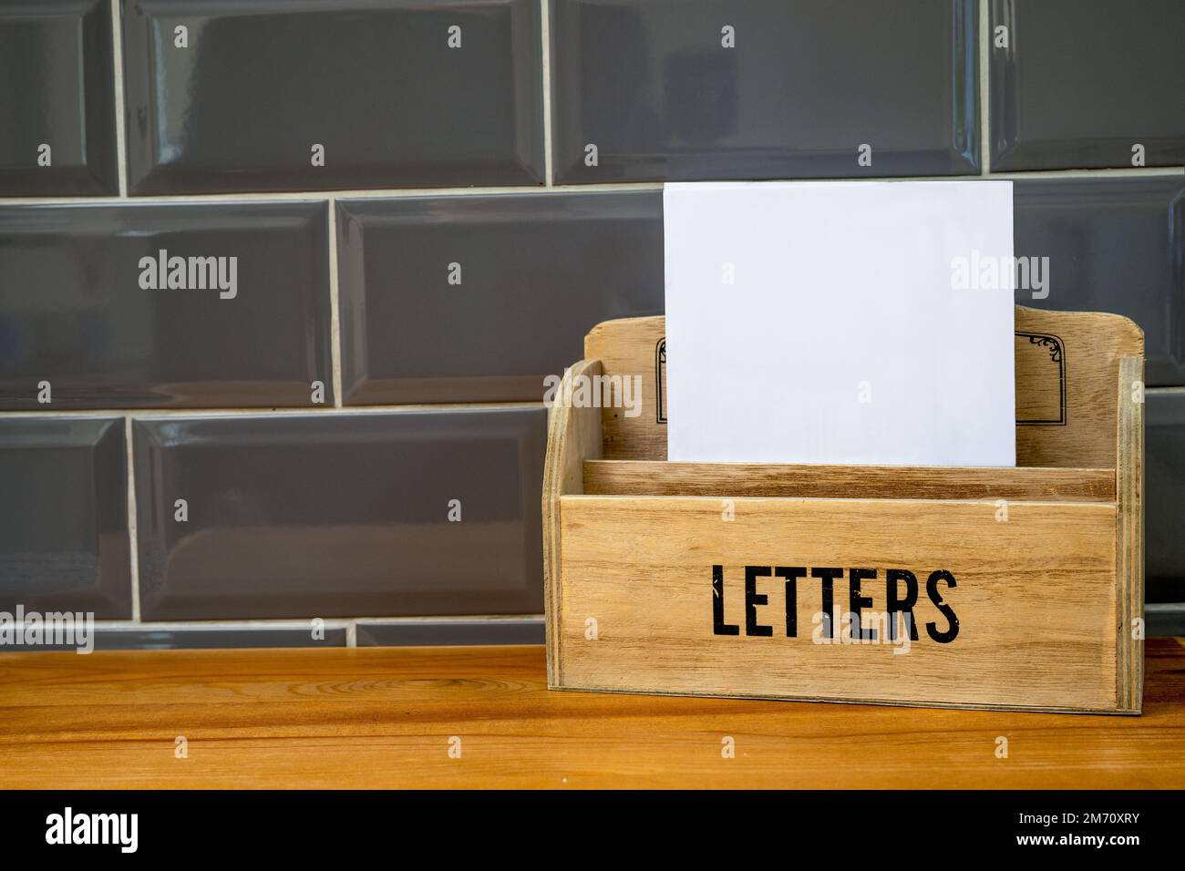 mail letter rack with blank paper on a wooden desk top and tiled walls ...