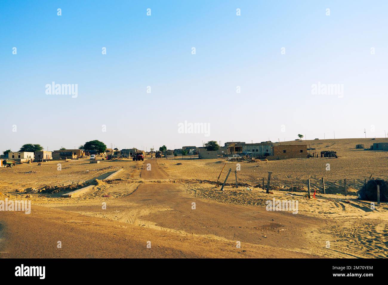 Empty road approaching remote desert village inside the desert. Distant ...
