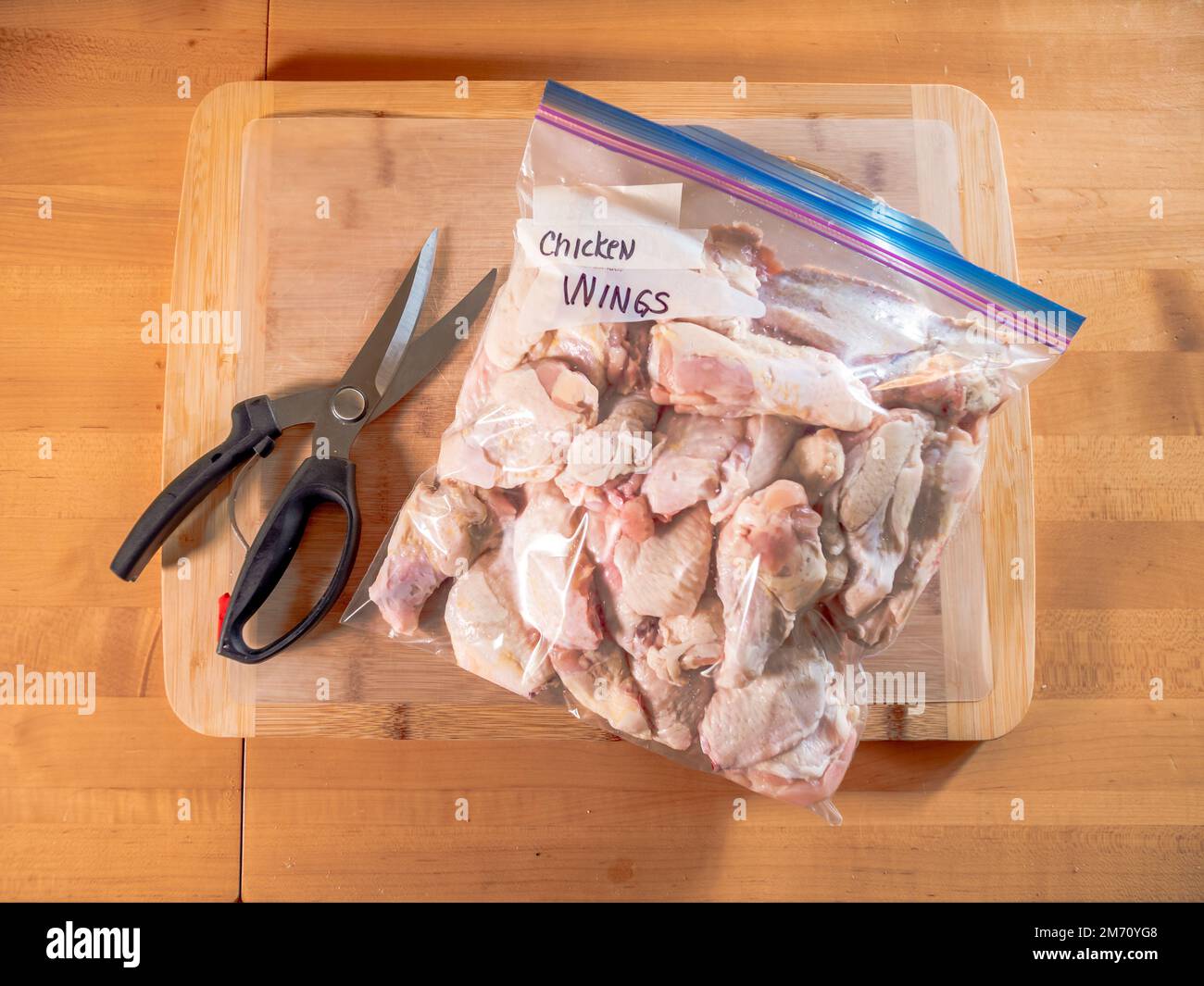 Raw chicken wings in freezer bag ready for freezing. Food shears and ...