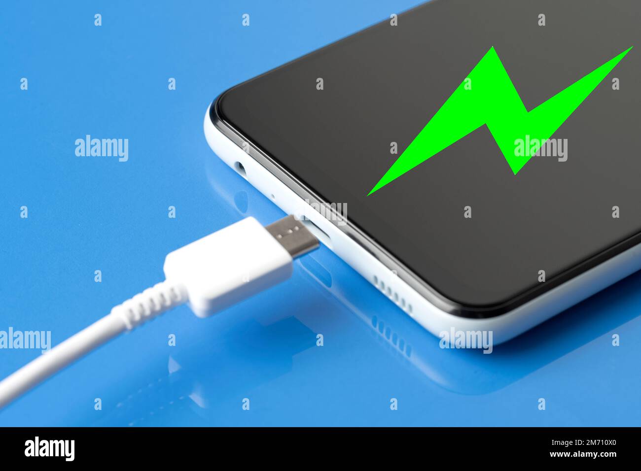 Charging a mobile smartphone on a blue glossy background Stock Photo ...